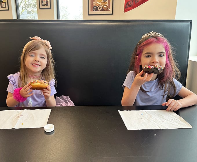 Young donut enthusiasts experiencing that universal moment of pure joy that comes with the first bite of something truly special.
