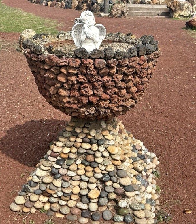Not your average garden planter—this volcanic rock chalice topped with a cherub proves even angels appreciate good stonework.