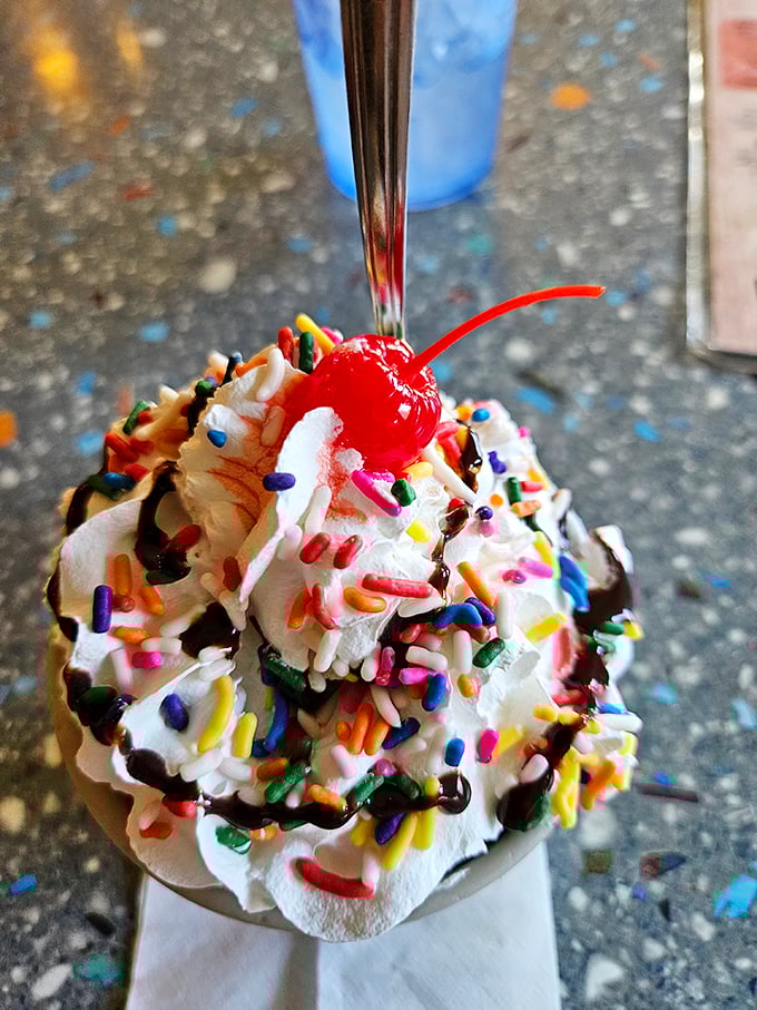 This isn't just ice cream—it's childhood joy in a dish, crowned with whipped cream, rainbow sprinkles, and that essential cherry on top.