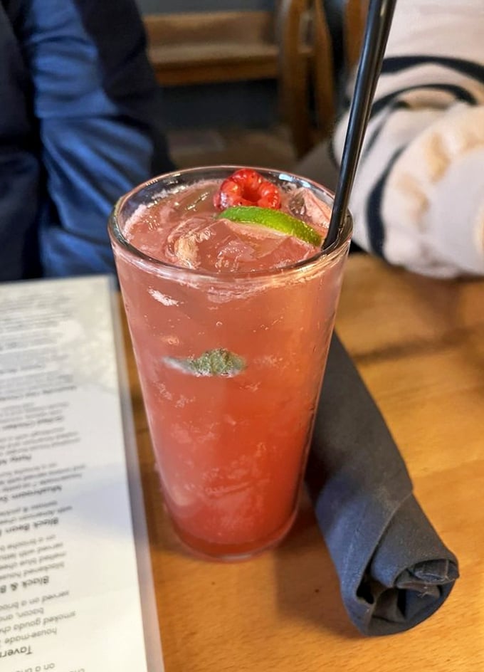 A raspberry cocktail that looks like summer in a glass. The lime and fresh berry garnish aren't just pretty—they're promising you refreshment.
