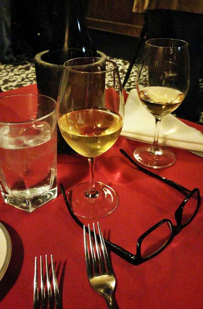 Wine glasses catching the light against that classic red tablecloth—a scene that whispers, "Tonight, we're not just eating, we're dining."