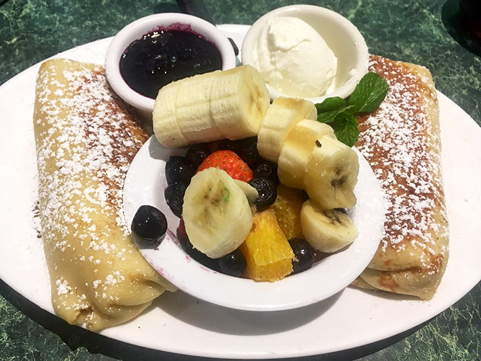 Breakfast crepes that understand fruit isn't just healthy—it's dessert in disguise. That powdered sugar snowfall seals the deal.