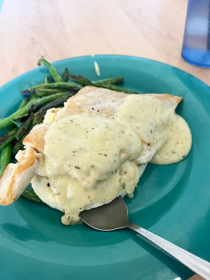 Herb-roasted chicken draped in velvety sauce alongside vibrant green asparagus – proof that diners can do elegant without pretension.