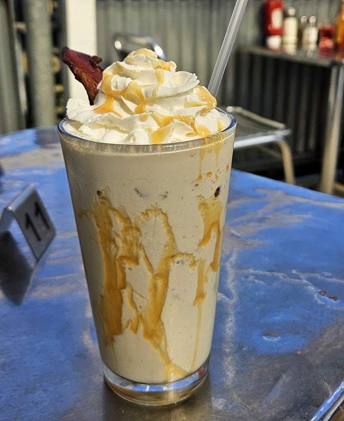 This isn't just a milkshake—it's dessert in a glass, topped with whipped cream and what appears to be candied bacon. Sweet meets savory!