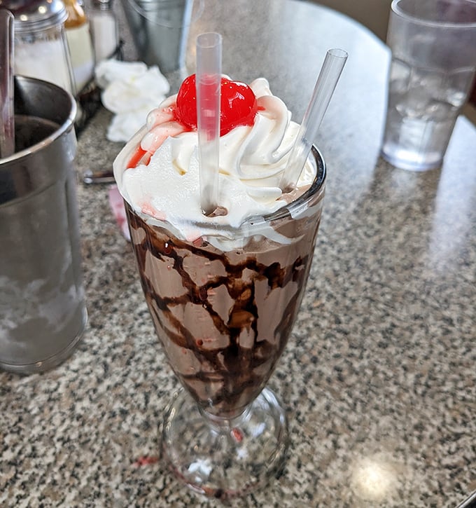 This chocolate milkshake isn't just a dessert – it's a tower of nostalgia topped with whipped cream, chocolate drizzle, and a cherry that's basically wearing a crown.