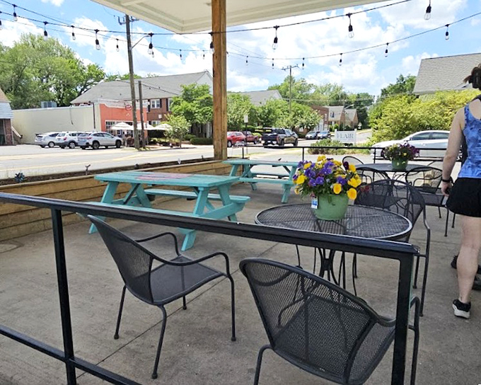 The outdoor seating area, where string lights and turquoise picnic tables create the perfect stage for your donut performance. Flowers add a touch of civilization.