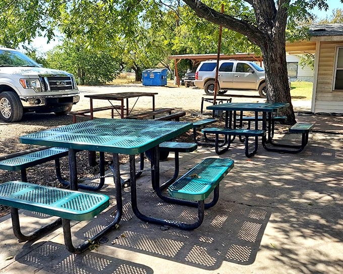 Outdoor seating under Texas skies where the shade trees and metal picnic tables create the perfect backdrop for burger bliss—nature's dining room.