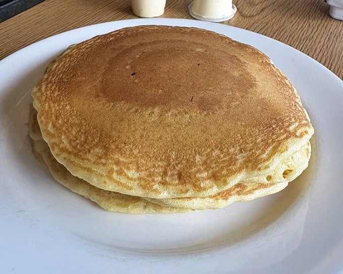 Pancakes so perfectly golden they belong in Fort Knox—fluffy enough to use as a pillow if you weren't so busy devouring them.