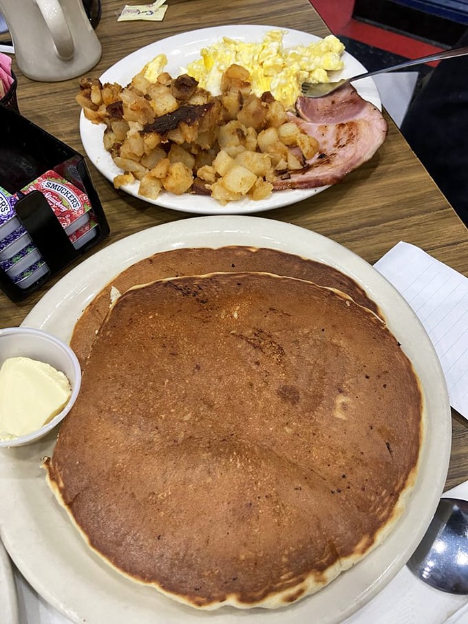 That pancake isn't just large—it's the size of a small frisbee, ready to soak up syrup like it's been training for this moment.