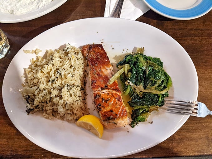 Simple yet spectacular: grilled salmon rests beside herb-flecked rice and sautéed greens, proving that sometimes the most straightforward dishes deliver the most profound satisfaction.