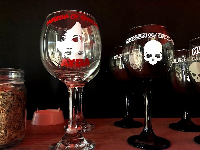 Souvenir glasses featuring Ayda's haunting visage—because nothing says "I survived" like sipping wine from a vessel adorned with the paranormal.