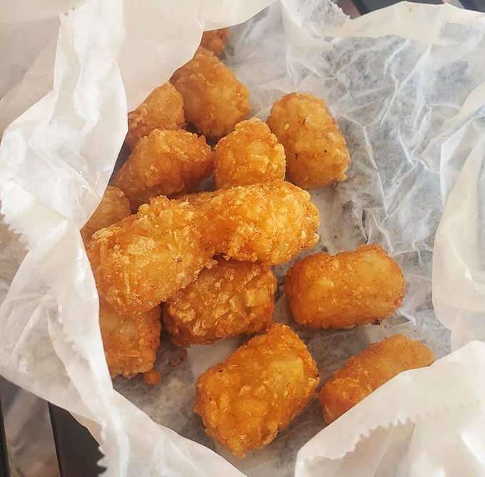 Golden-brown tater tots nestled in wax paper—childhood nostalgia with a crispy exterior and fluffy interior.