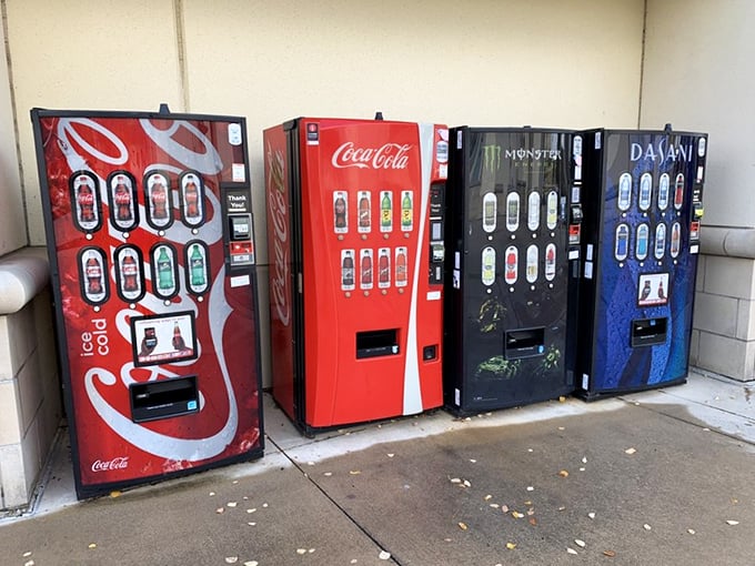 The vending machine lineup—silent sentinels offering liquid courage to continue the shopping marathon. That Coca-Cola machine has witnessed countless retail therapy sessions.