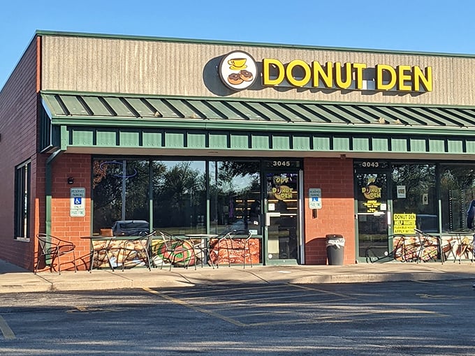 Donut Den's bright yellow sign pops against its brick and green exterior. Those outdoor tables are perfect for donut-based people watching.