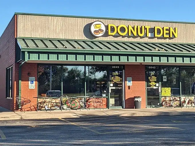Donut Den's bright yellow sign pops against its brick and green exterior. Those outdoor tables are perfect for donut-based people watching.