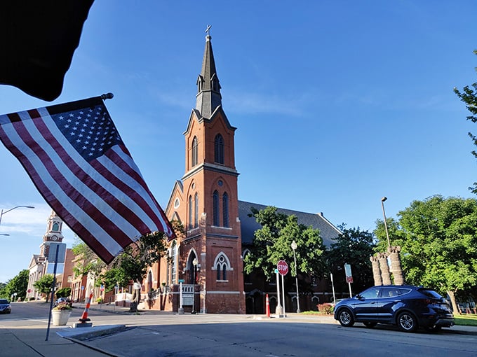 St. Joseph's church spire reaches skyward while Old Glory waves, creating a perfect postcard of American values.