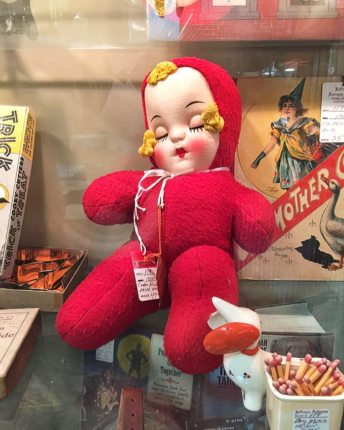 This sleeping beauty in cherry red chenille isn't just a doll—it's childhood comfort from an era before batteries required.