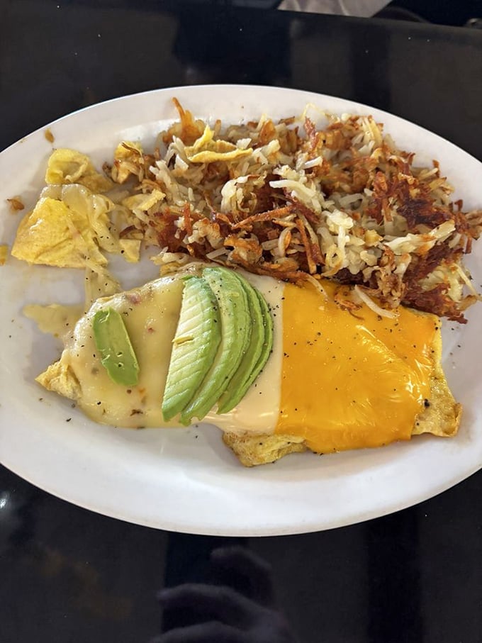 Breakfast artistry at its finest – a three-cheese omelet that stretches the definition of "portion control" in the most delicious way possible.