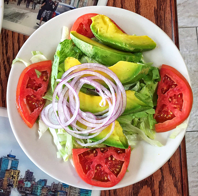 A symphony in green and red—this avocado and tomato salad offers a refreshing counterpoint to Cuba's heartier classics.