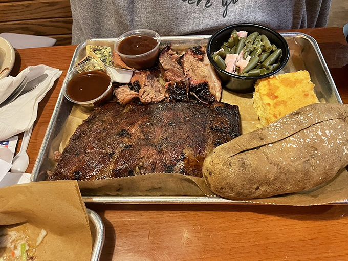 A barbecue platter that means business – smoke-ringed brisket, tender pork, green beans, and cornbread that's ready for its close-up.