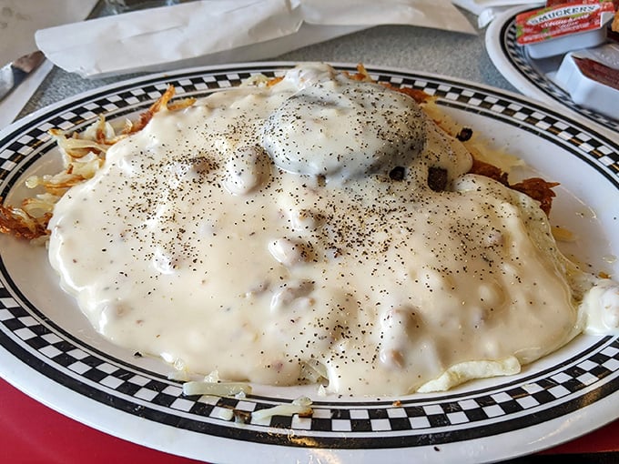 Beneath that pepper-speckled blanket of country gravy lies a breakfast that could fuel a farmhand—or just you on a lazy Sunday.
