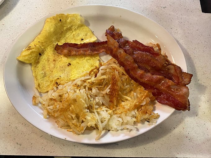 The holy trinity of breakfast perfection: fluffy scrambled eggs, hash browns with that essential crispy edge, and bacon cooked to that ideal point between chewy and crisp.
