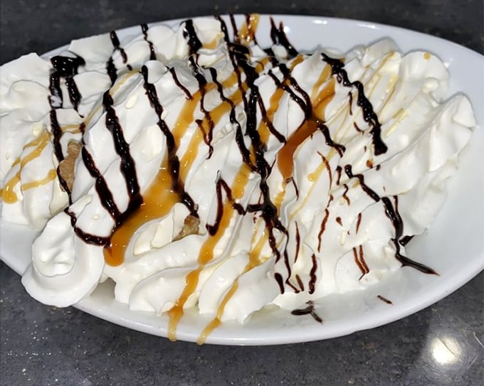 This mountain of whipped cream, drizzled with chocolate and caramel, isn't just dessert—it's performance art that happens to be delicious.