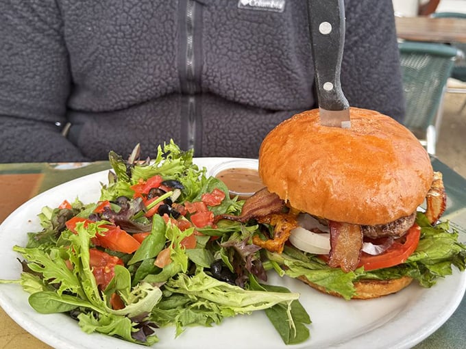 The burger that launched a thousand return visits – perfectly stacked, nestled in a pillowy bun, with a salad trying to claim it's health food.
