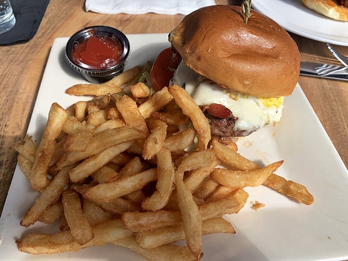 A burger that requires both hands and a strategy – crispy fries standing at attention beside a sandwich that's more monument than meal.