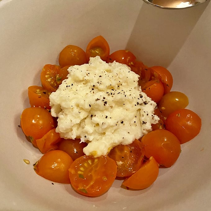 Cherry tomatoes surround creamy burrata like devoted admirers – a simple combination that proves sometimes less really is more.