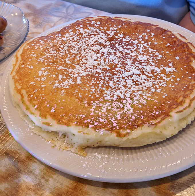 This pancake isn't just large—it's territorially ambitious. The powdered sugar snowfall adds that touch of sweetness that makes mornings worthwhile.