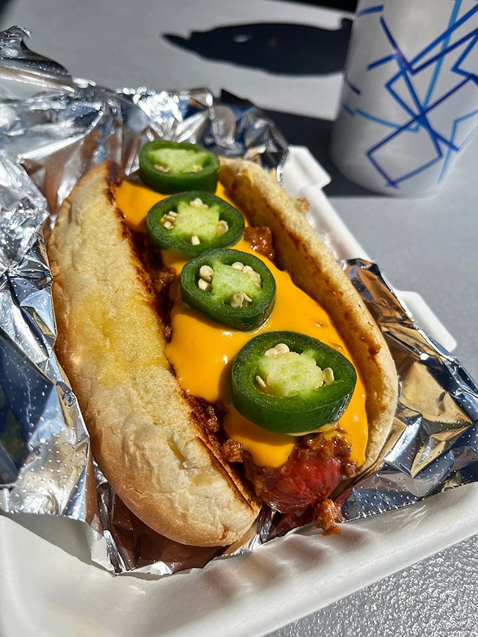 The chili cheese dog arrives loaded with jalapeños, proving paradise sometimes comes with proper heat.