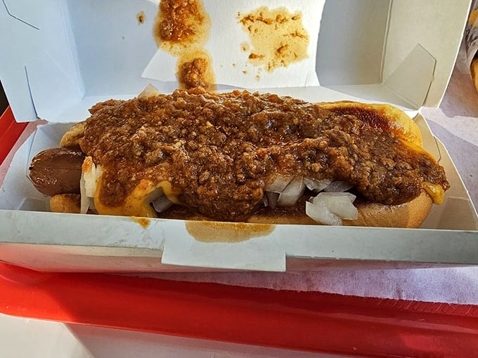 The chili dog in its natural habitat—nestled in a paper boat, surrounded by fries, waiting to transform your ordinary lunch into a moment of pure joy.