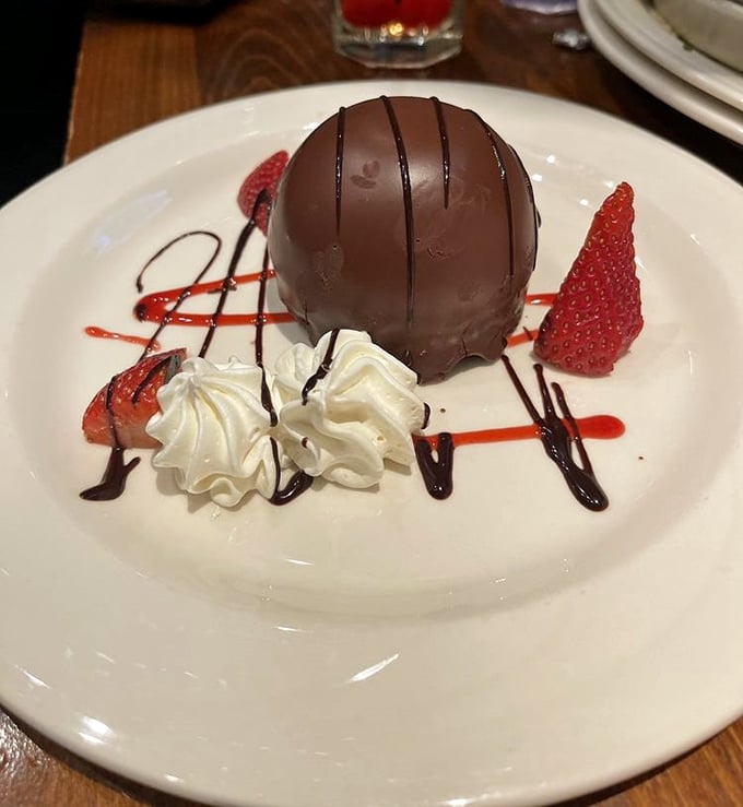 The chocolate bomb dessert arrives like a sweet meteor of joy. Surrounded by fresh berries and whipped cream, it's a celestial end to any meal.