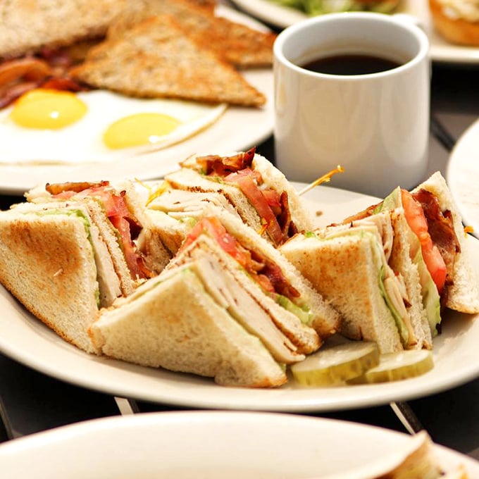The club sandwich—an engineering marvel of bread, meat, and vegetables that requires both hands and a strategy. Worth every bite.