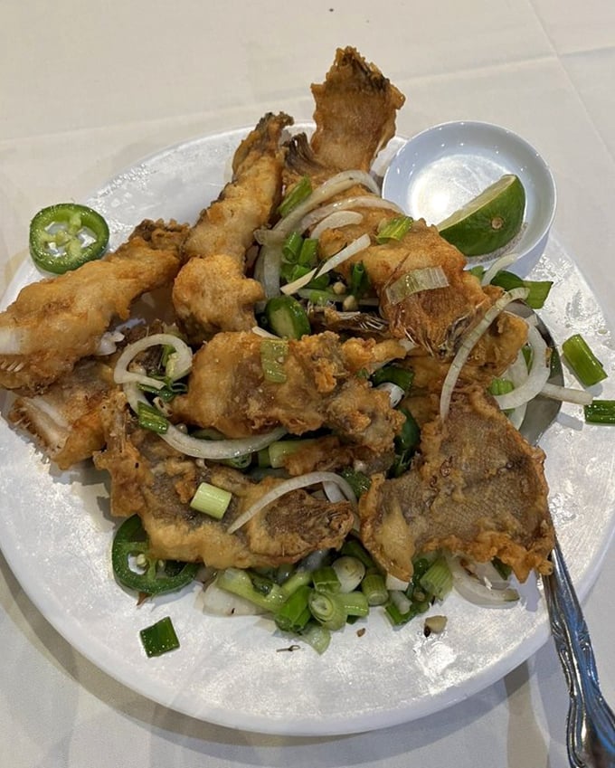 Crispy fried fish that shatters like glass when touched, adorned with a confetti of jalapeños, onions, and herbs.