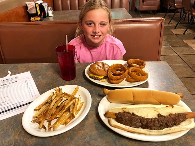 A young diner contemplates the serious business of onion rings, burgers, and fries—learning early that life's greatest pleasures often come on plain white plates.