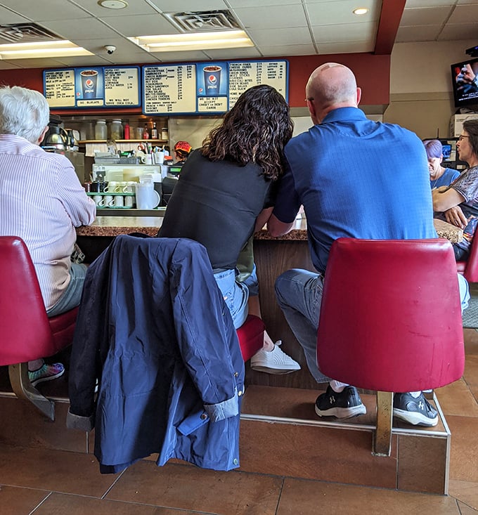 The counter seats—where regulars become family and first-timers become regulars after just one perfectly charred burger experience.
