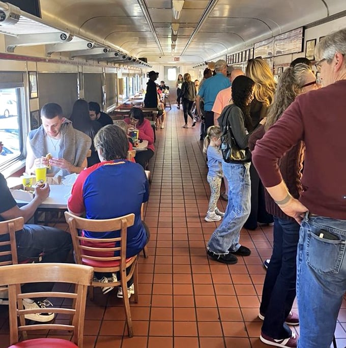 The narrow dining car creates an intimate experience where strangers become temporary neighbors, united by the universal language of great food and train car ambiance.