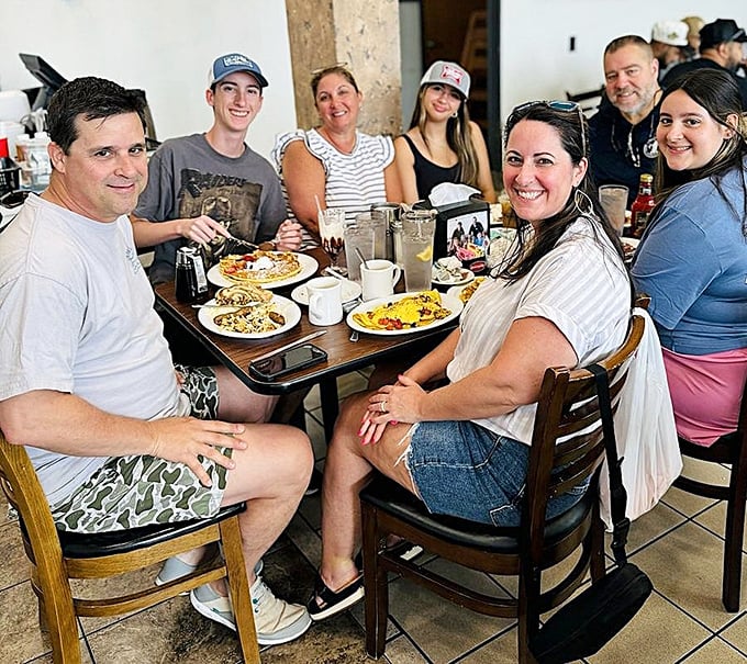 Happy diners gathering around breakfast—the universal language of morning joy spoken fluently at The Pancakery's wooden tables.