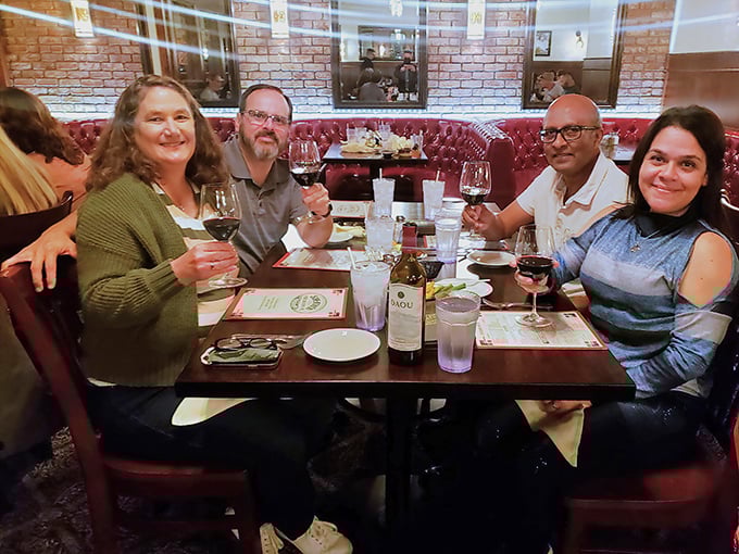 The universal language of "this food is amazing" spoken through raised wine glasses. These diners aren't just eating dinner—they're creating memories around that bottle of red.