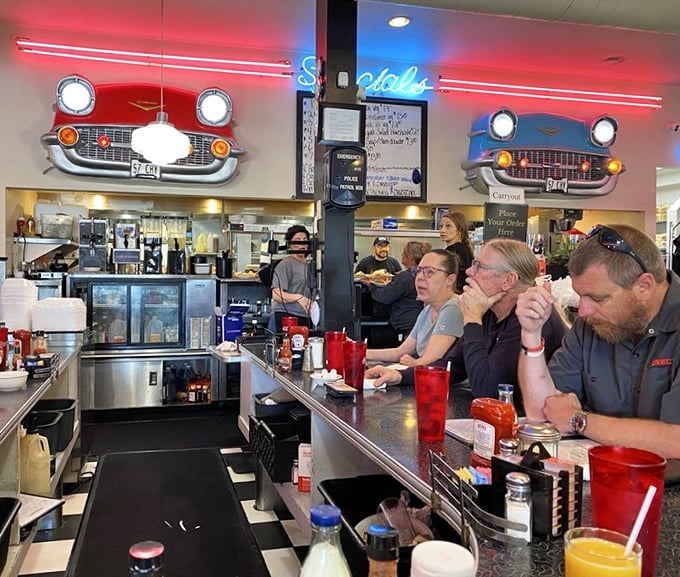 The counter seating—where solo diners become part of the Tommy's family and vintage car fronts watch over your meal like chrome guardians.