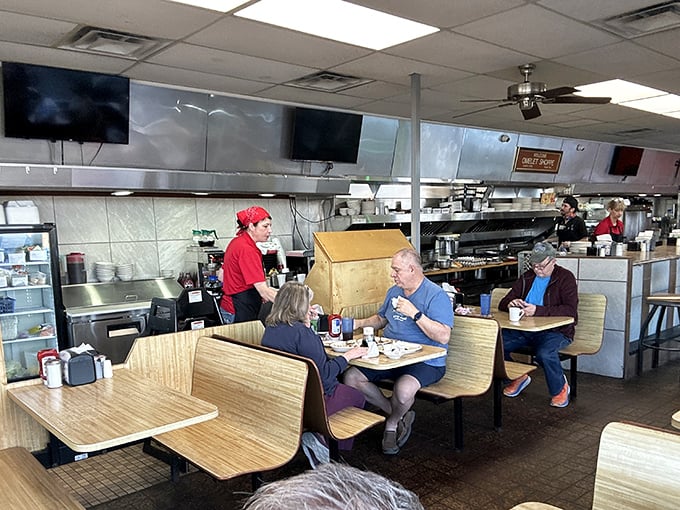 The diner in action—servers in red, wooden booths, and hungry patrons. That open kitchen concept existed long before trendy restaurants claimed to invent it.