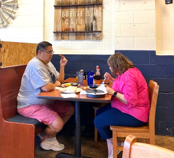Every booth tells a story, and these diners are writing theirs one forkful at a time against a backdrop of simple blue walls.
