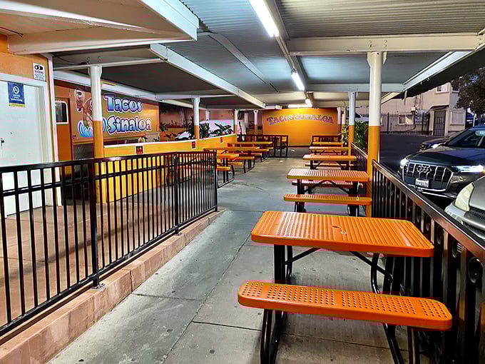The covered dining area offers a no-frills spot to worship at the altar of great tacos. Orange tables match the truck—commitment to branding or happy accident?