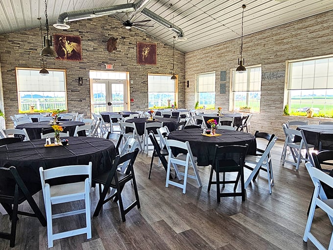 The dining room dressed in black and white, with sunlight streaming through windows framing countryside views – farmhouse elegance without pretension.
