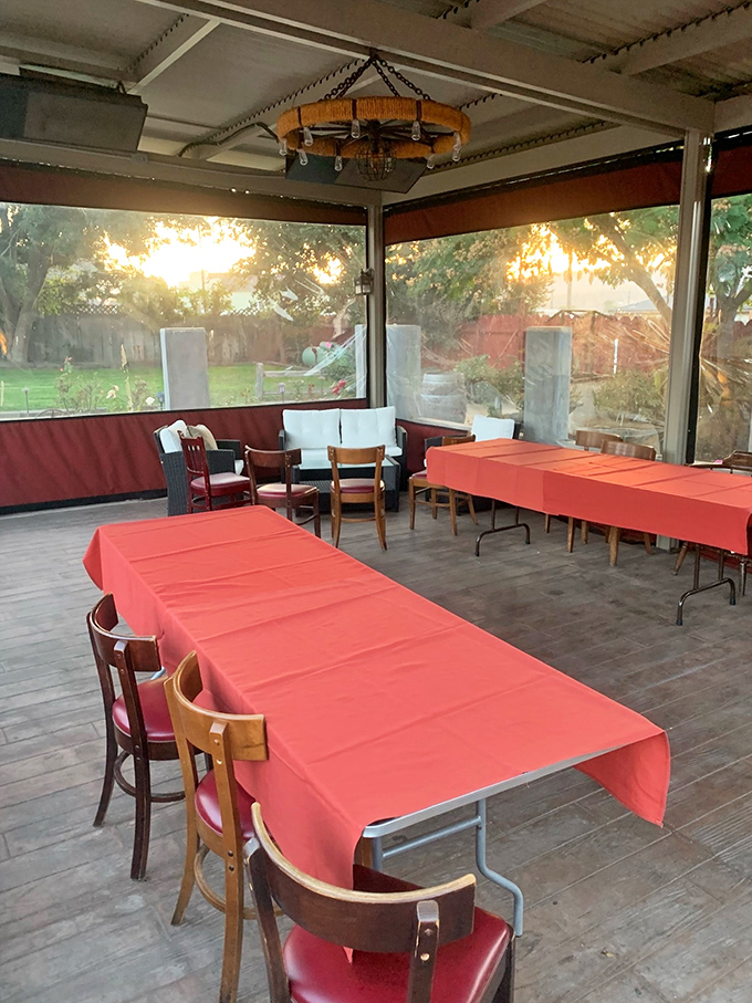 The covered patio offers a sunset view with your supper—orange tablecloths echo the golden hour glow filtering through the screens.