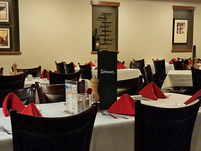 Classic supper club elegance: white tablecloths, dark wood chairs, and red napkins create the stage where memorable meals become family stories.