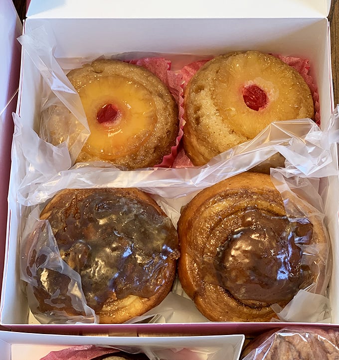 Pineapple upside-down donuts and glazed delights nestled in a bakery box—proof that good things really do come in small, hand-held packages.