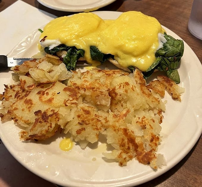 Eggs Benedict with a blanket of hollandaise that would make Julia Child nod in approval, paired with hash browns that crackle with each forkful.